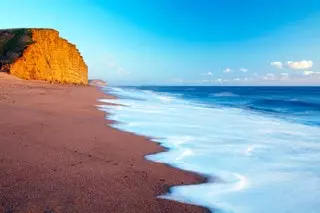 Burton Bradstock Dorset ด้วยหน้าผาที่พังทลายเป็นสีน้ำผึ้งและซากดึกดำบรรพ์จาก Jurassic Coast Burton...